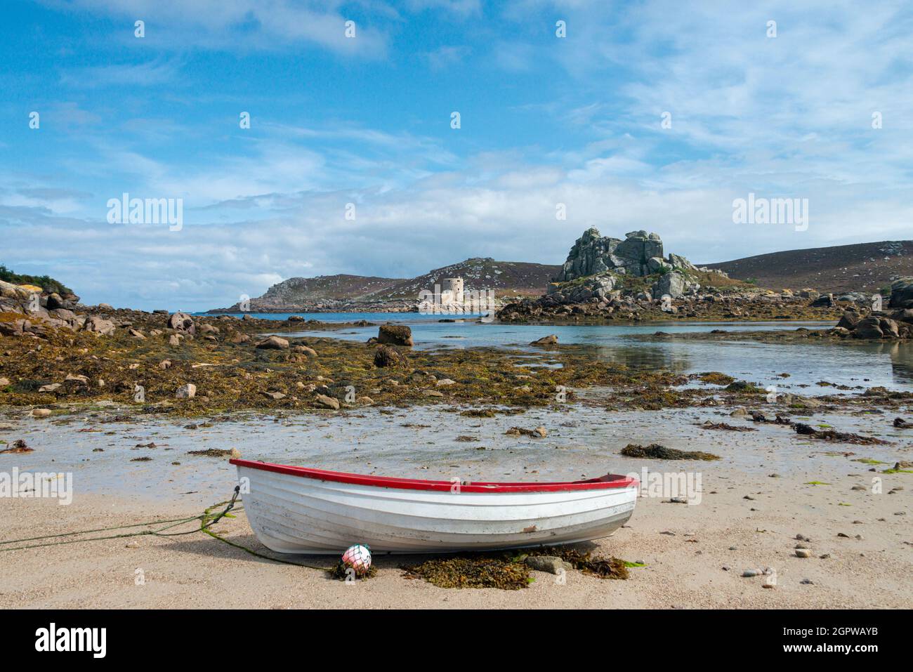 A red and white wooden boat on the beach at Kitchen Porth, Bryher ...