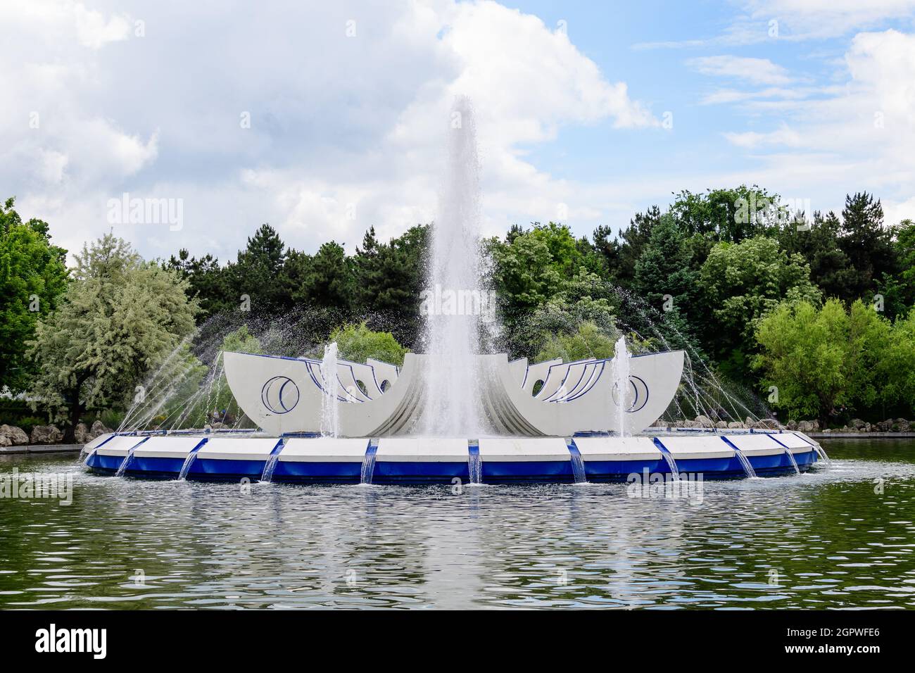 Landscape with the lake, decorative fountain and vivid green trees in ...