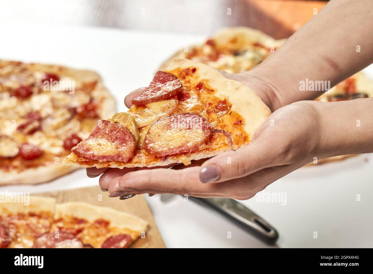 Hand holding a homemade pizza slice Stock Photo - Alamy