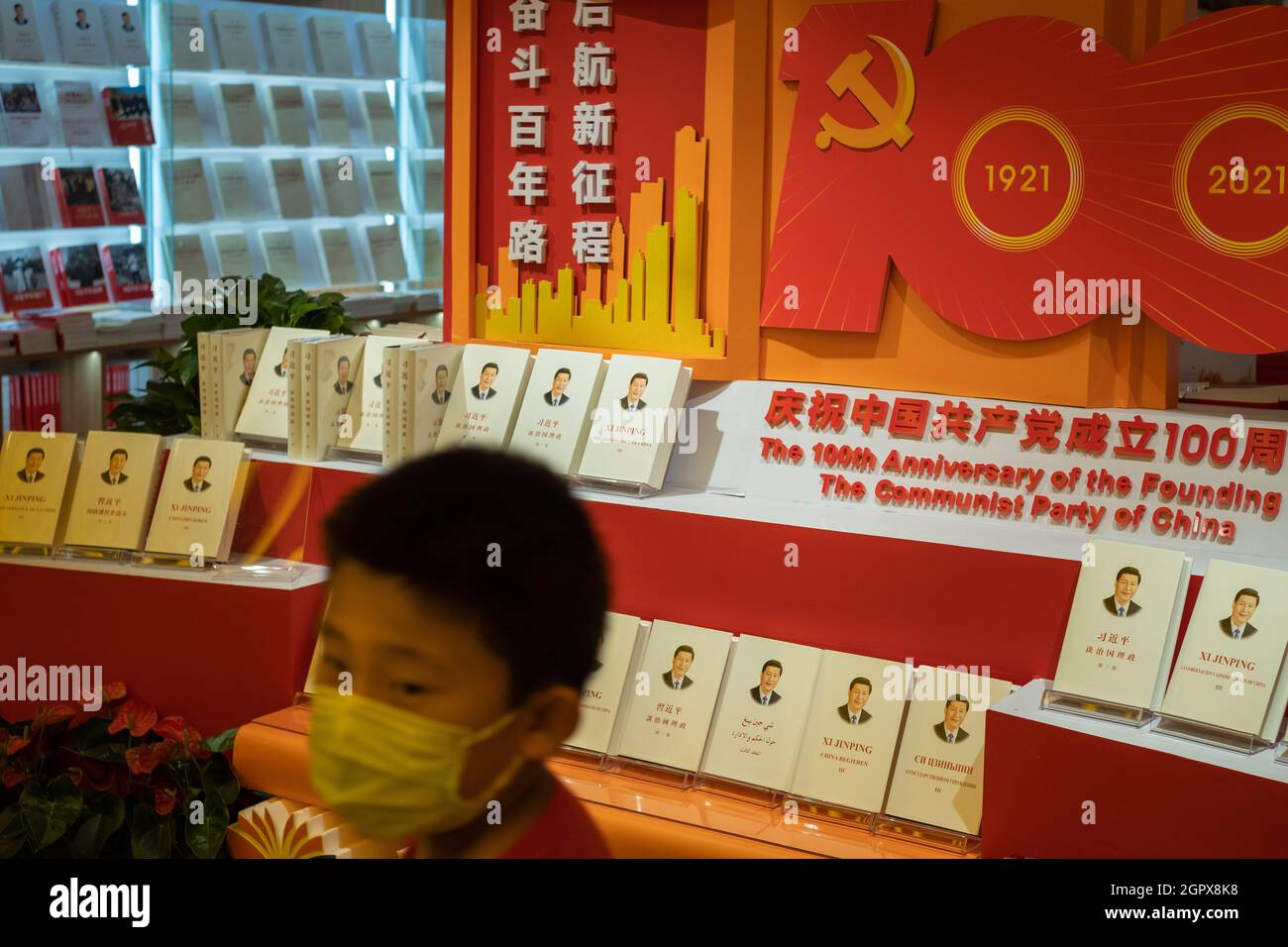 A boy walks past multilingual copies of "Xi Jinping: The Governance of ...