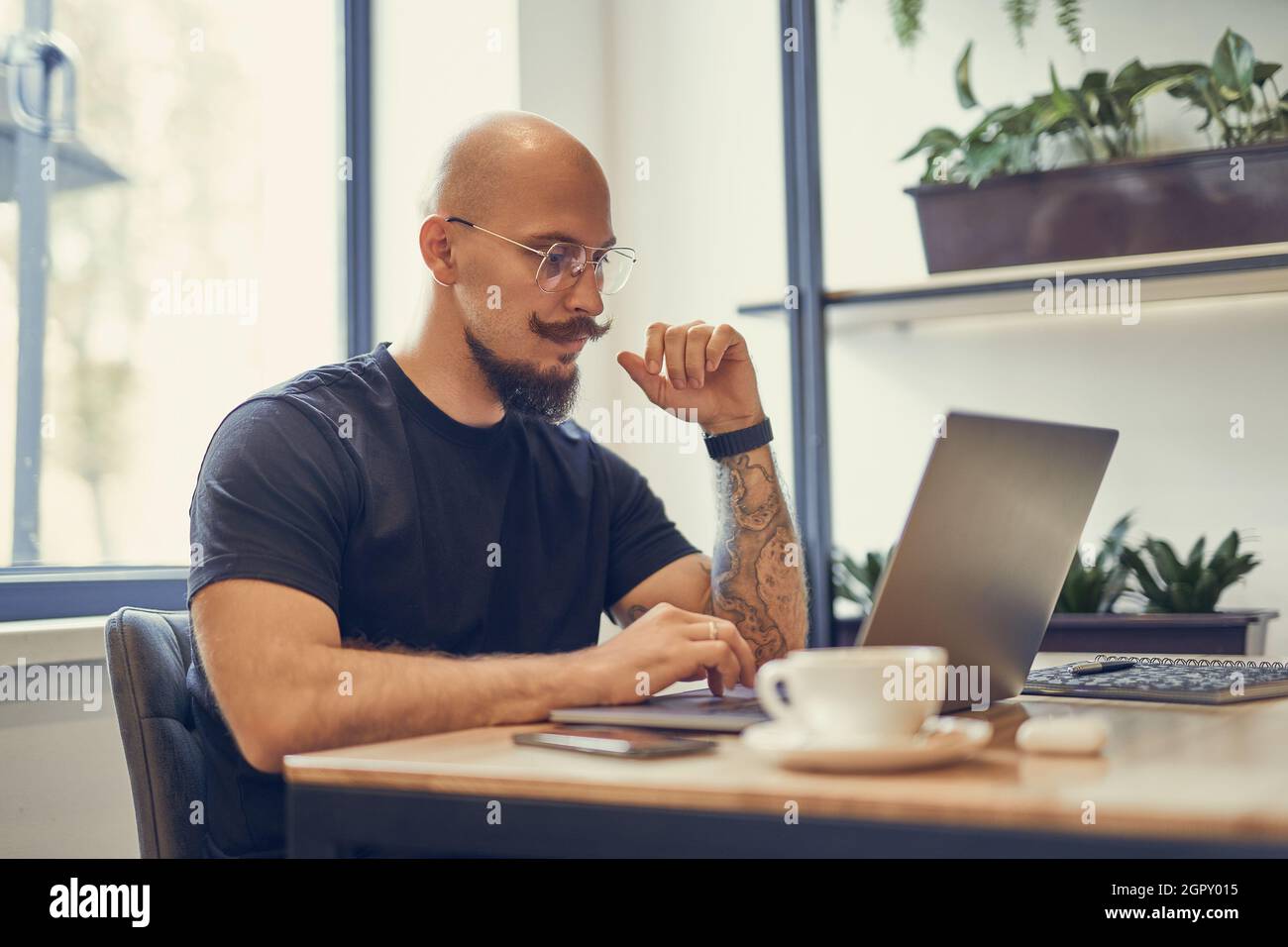 Bolded man with mustache and beard works on computer at home office ...