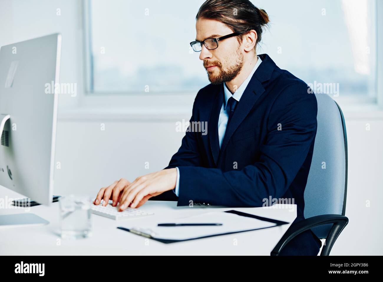 male manager sitting at a desk in front of a computer technologies ...