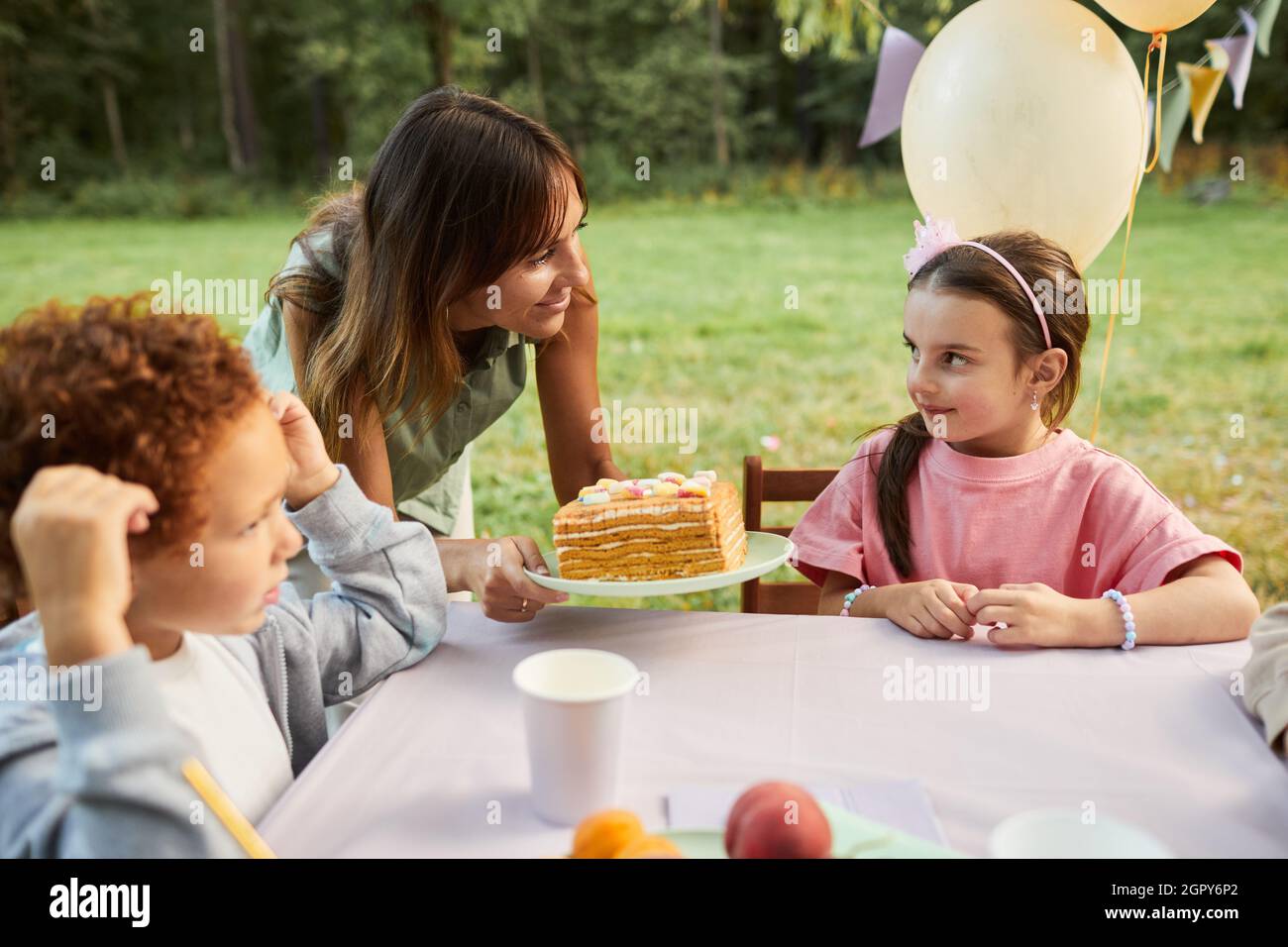 Portrait of smiling mother bringing Birthday cake to little girl during ...