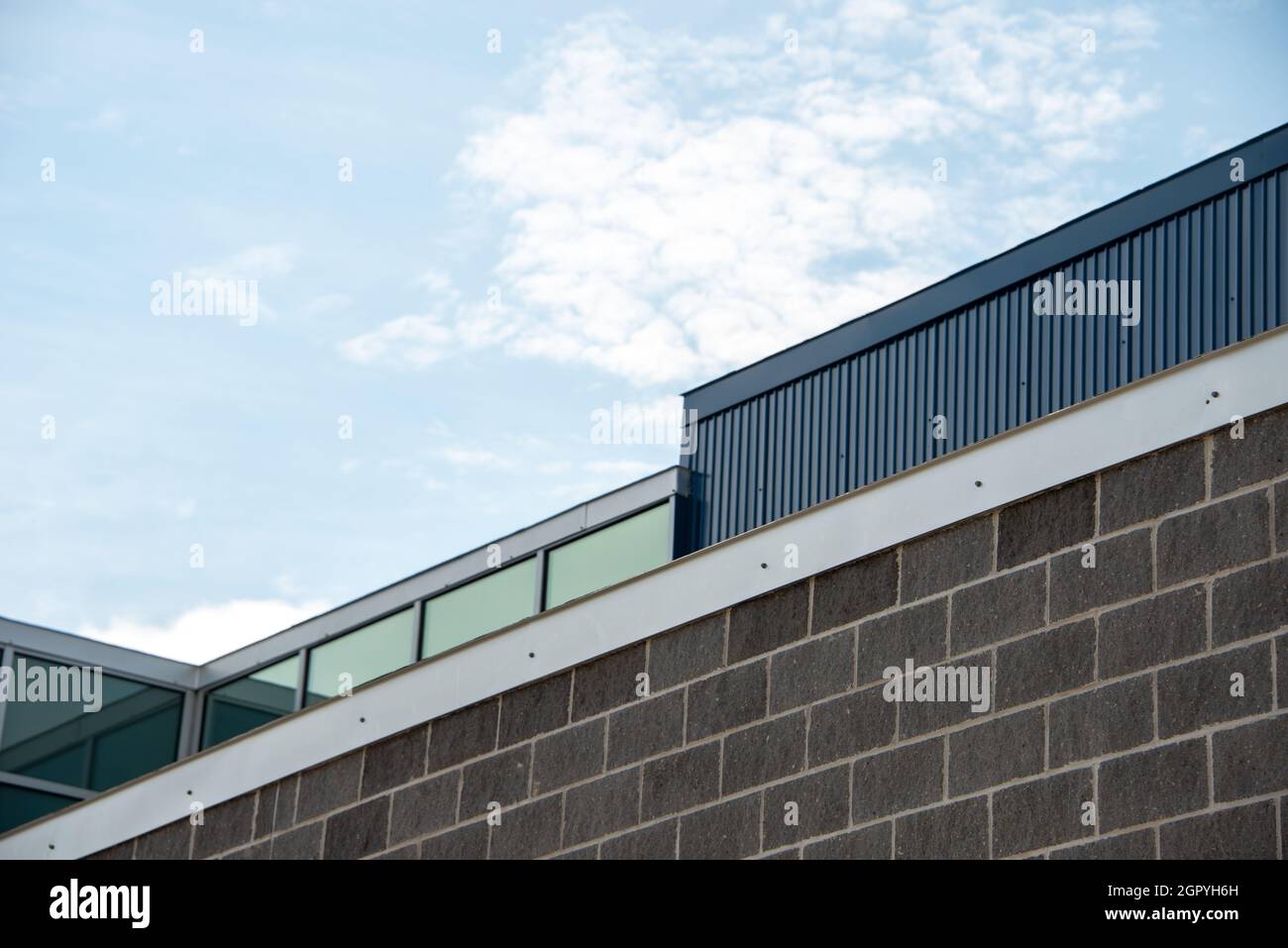 Exterior corner of a building with glass windows, a wall of blue metal ...