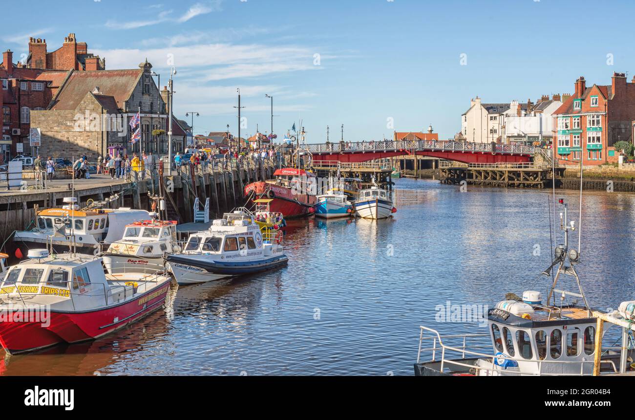 Buildings line the waterside and boats are moored underneath. A red ...