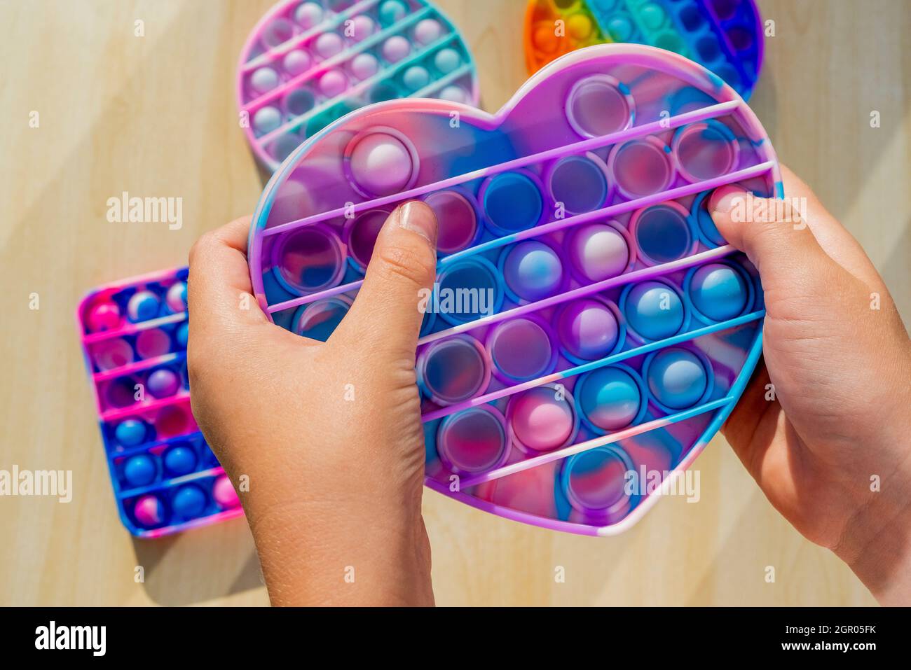 Little child playing with anti stress sensory pop it at wooden table ...