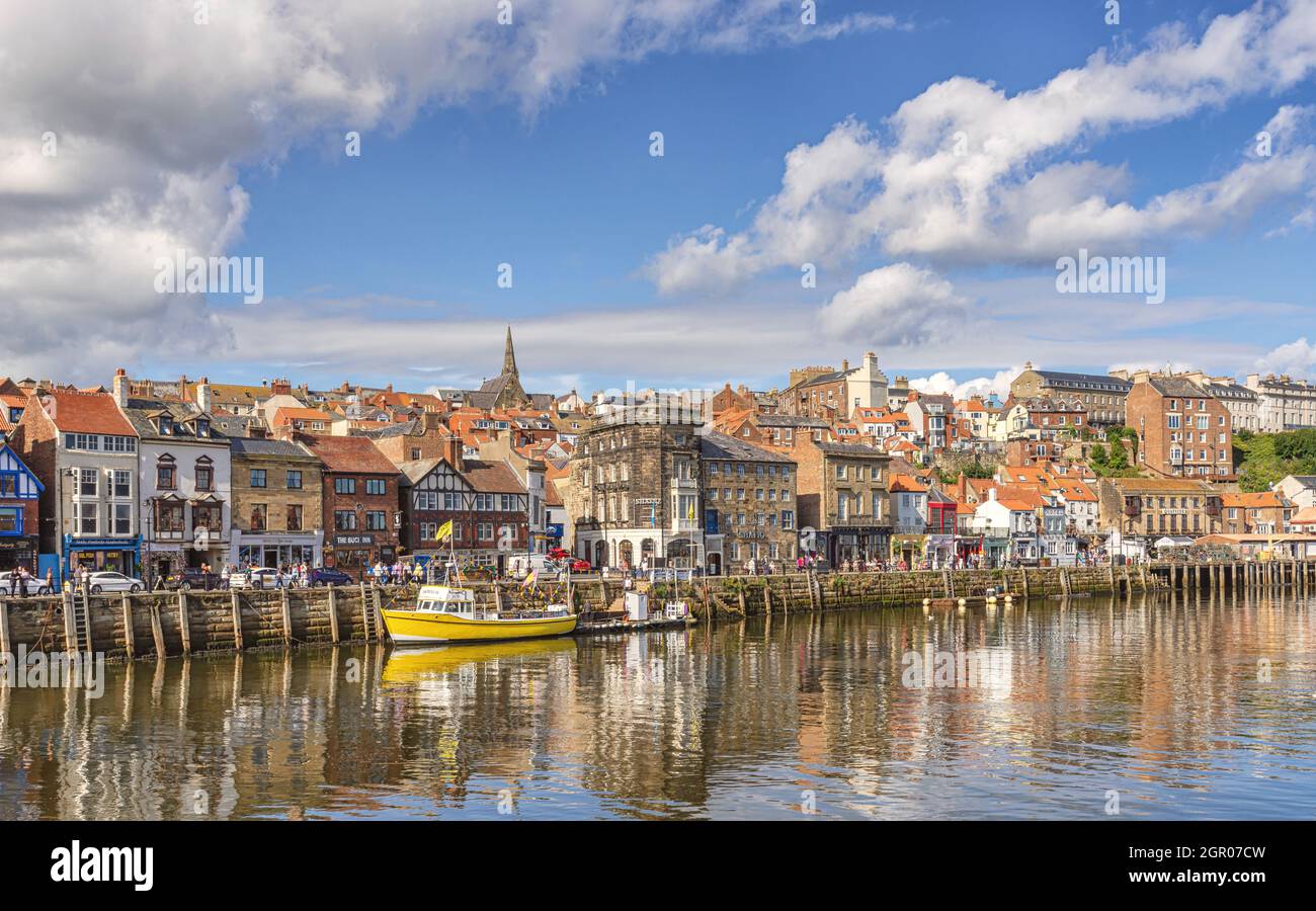 A panorama of seaside town and harbour. Buildings line the waterfront ...