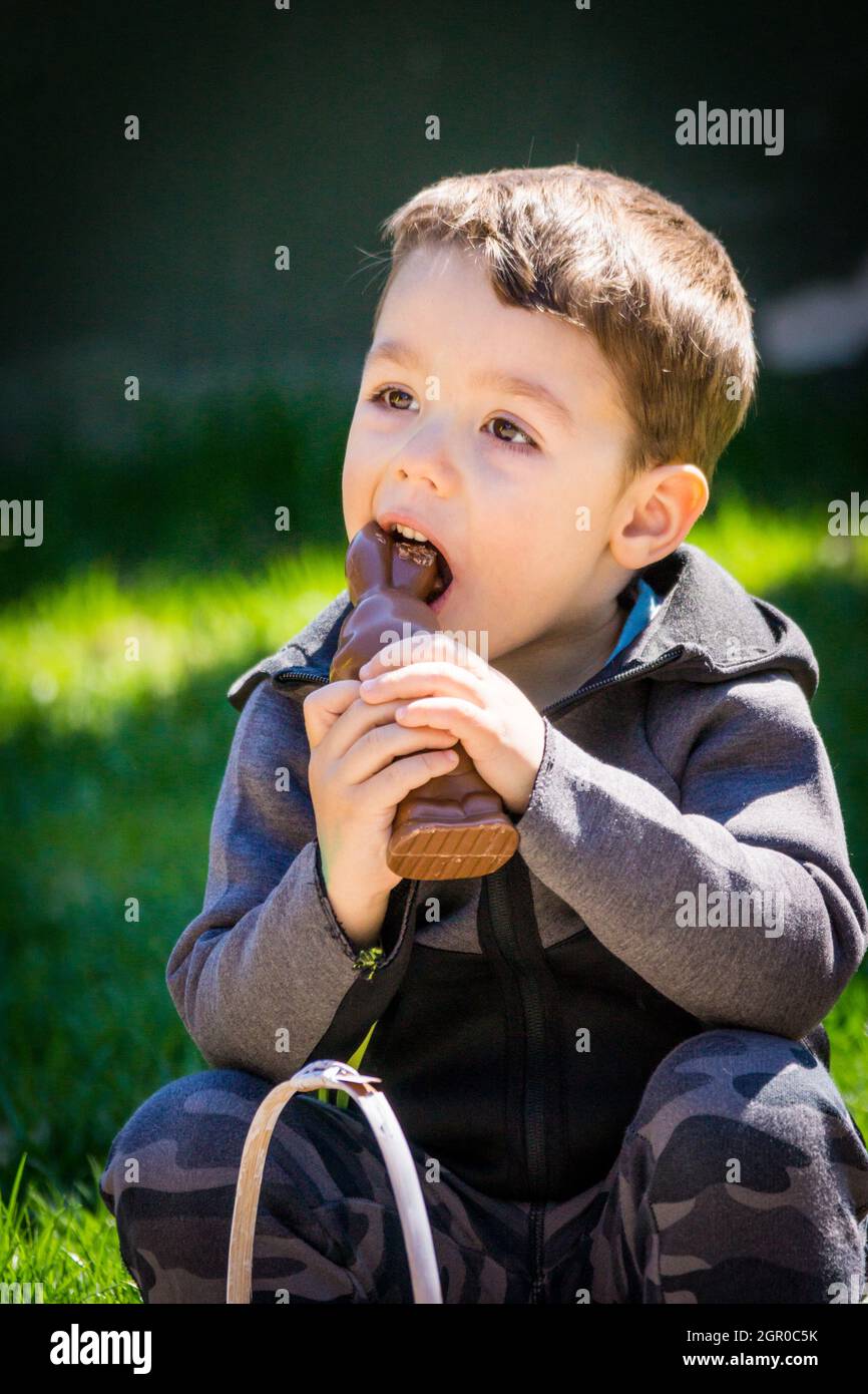 Cute Boy Eating Chocolate While Sitting Outdoors Stock Photo - Alamy