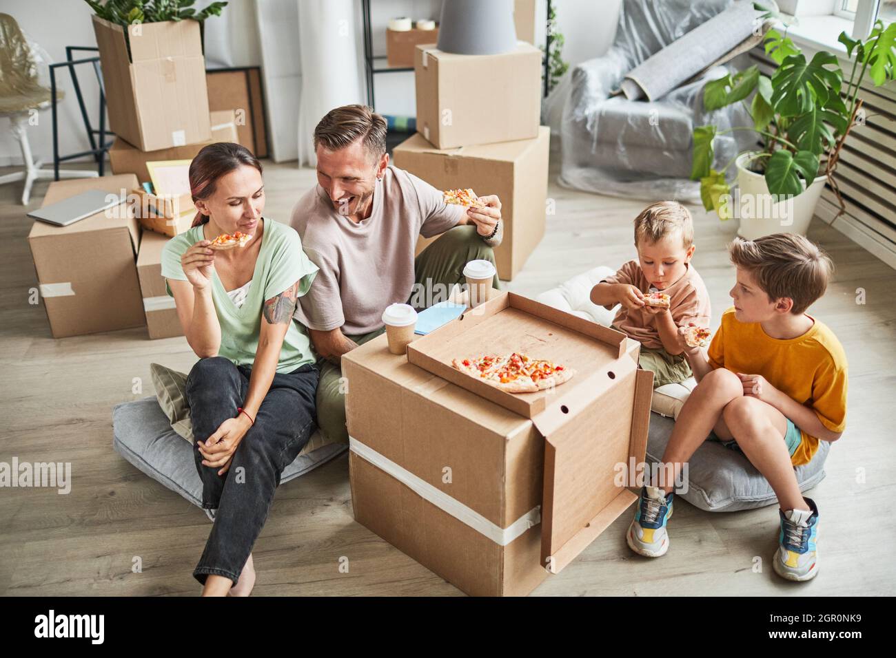 Full length portrait of happy family eating pizza from cardboard box ...