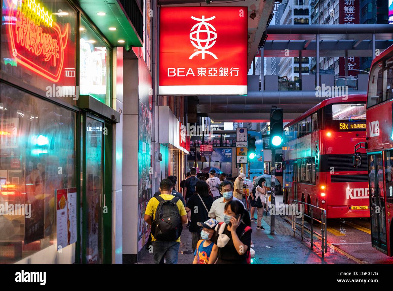 Pedestrians walk past the Bank of East Asia (BEA) branch and logo seen ...