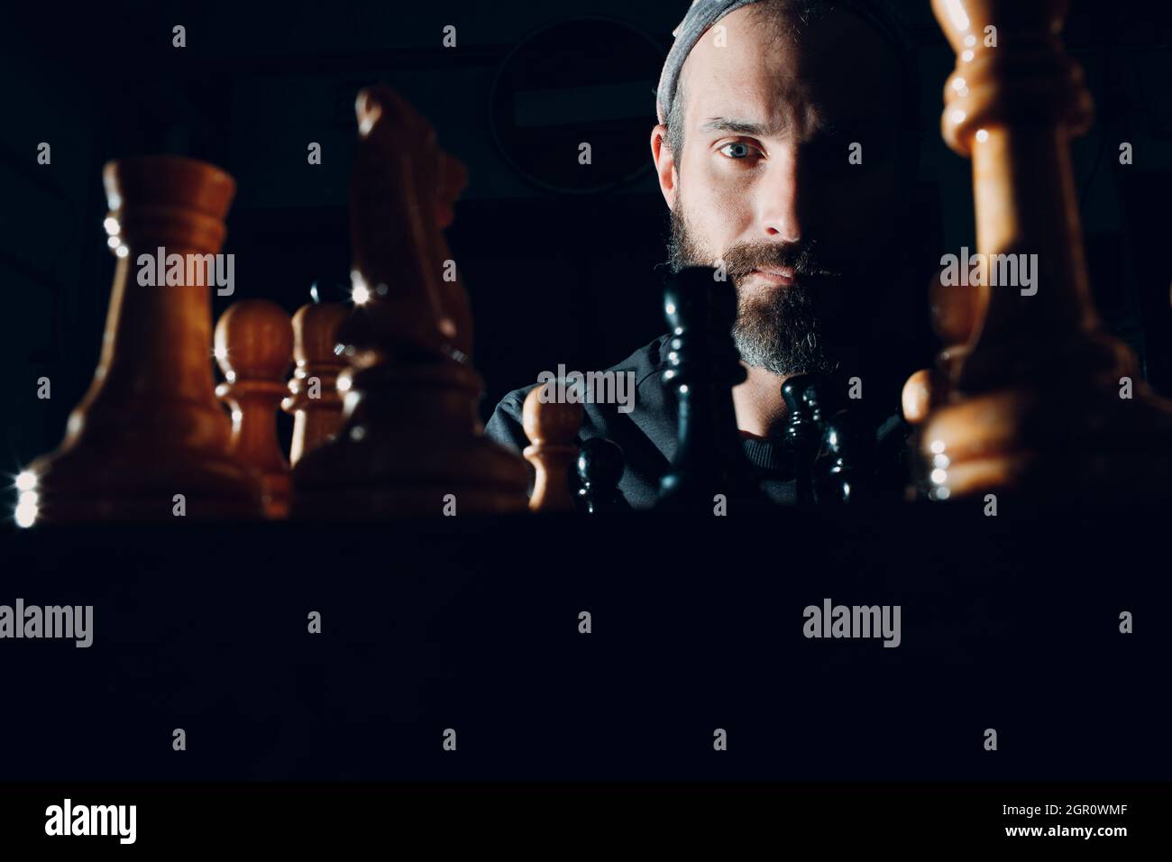 Young adult handsome man playing chess in dark with side lit Stock ...