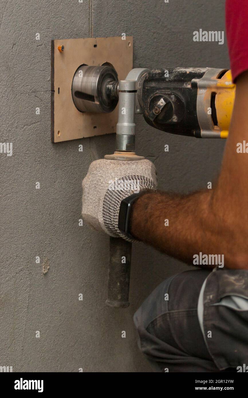 The technician uses a drill to drill a hole in the wall to install an ...