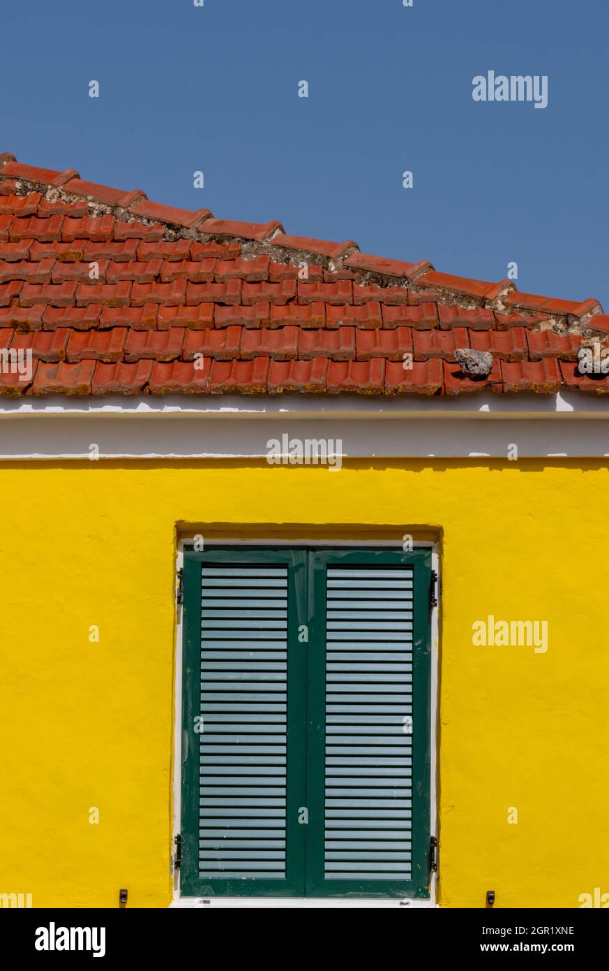 brightly painted yellow greek house with green wooden shutters and ...