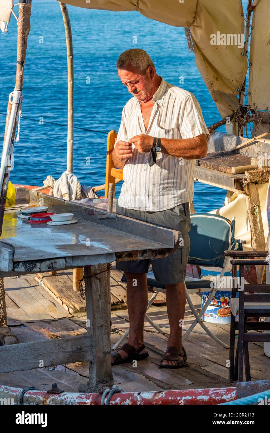 greek fisherman working on his boat in the harbour of zakynthos town on ...