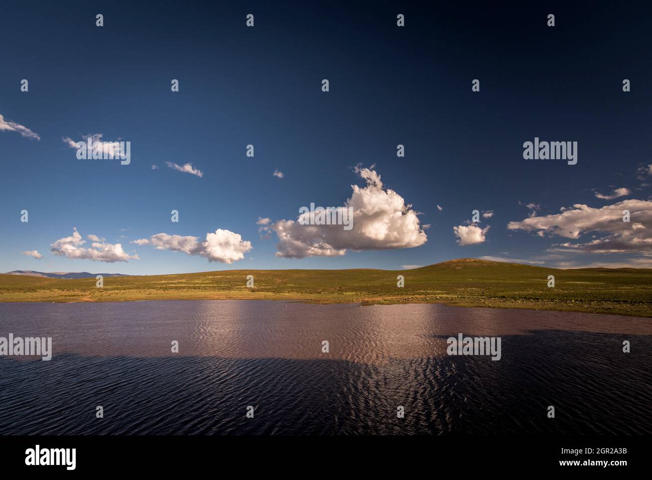 Perfect horizon view with water, green field, and clouded sky ...