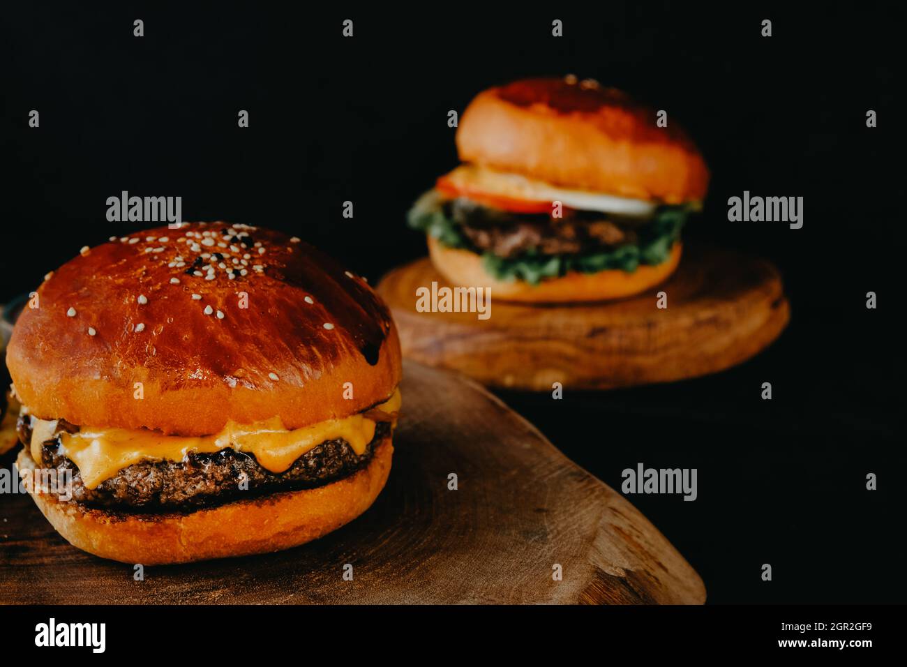 Hamburger on wooden plate with fries and small bowl of mayonnaise on ...