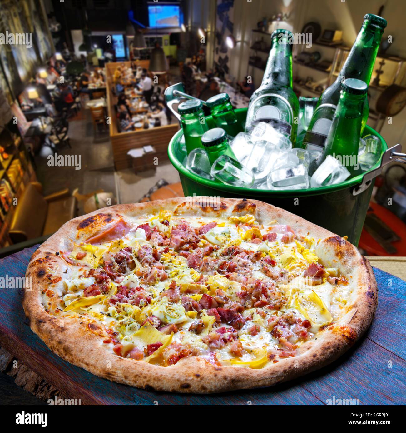 Bacon pizza, beer in an ice bucket at the pizzeria Stock Photo - Alamy