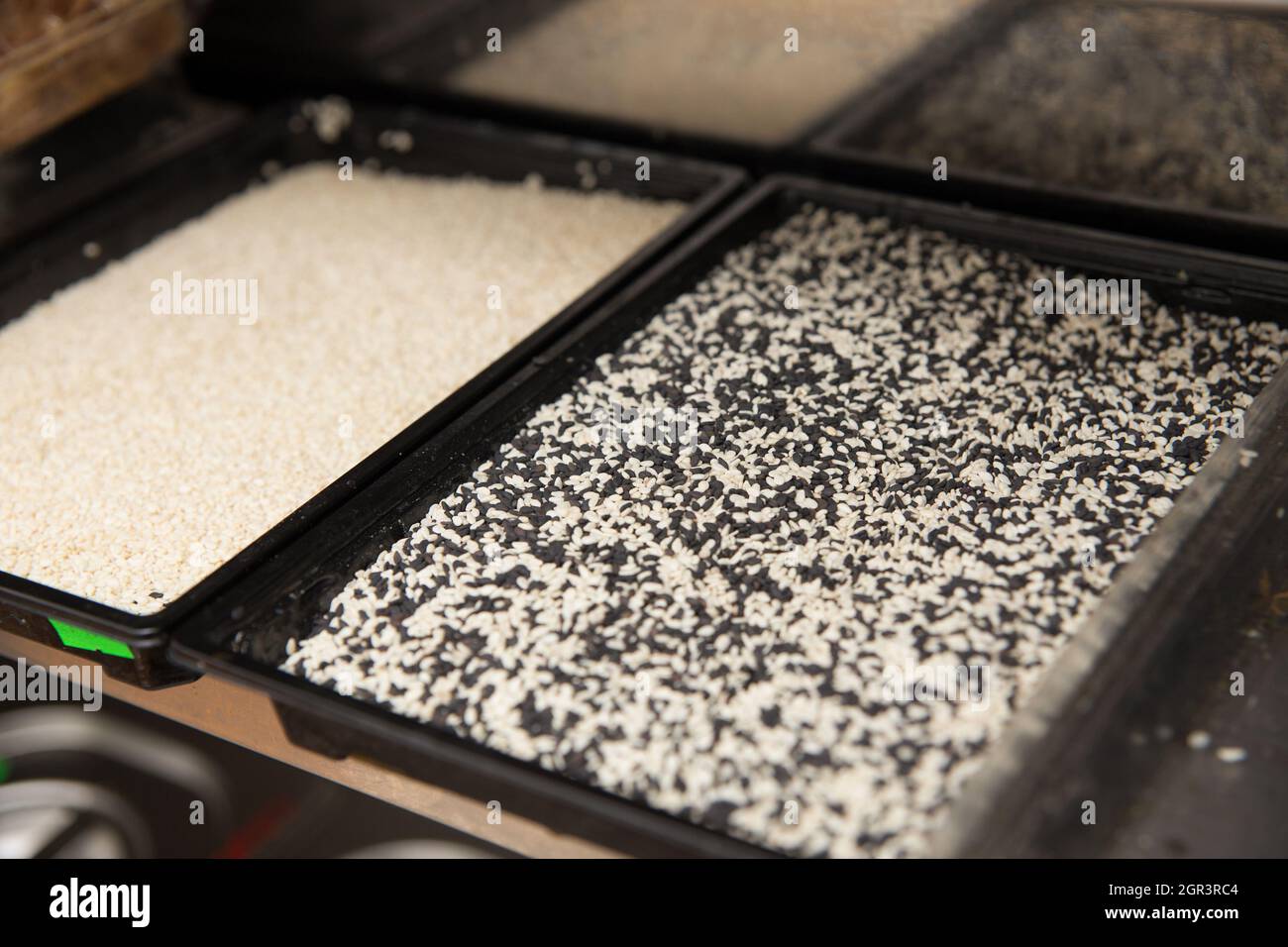 Plastic containers with white and black sesame seeds at the chef's ...