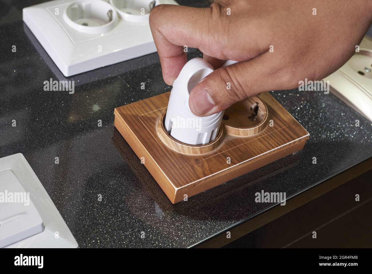 Hand testing a plug on a double socket in a store Stock Photo - Alamy