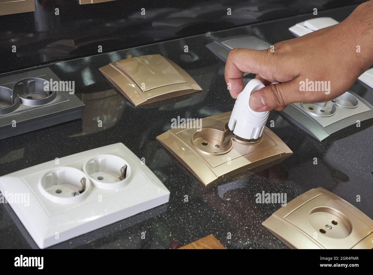Hand testing a plug on a double socket in a store Stock Photo - Alamy