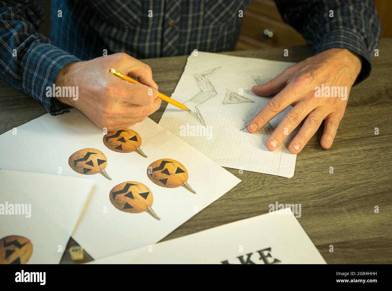 How to make Jack O'Lantern at home? Male hands with a pencil preparing a template for cutting a ...