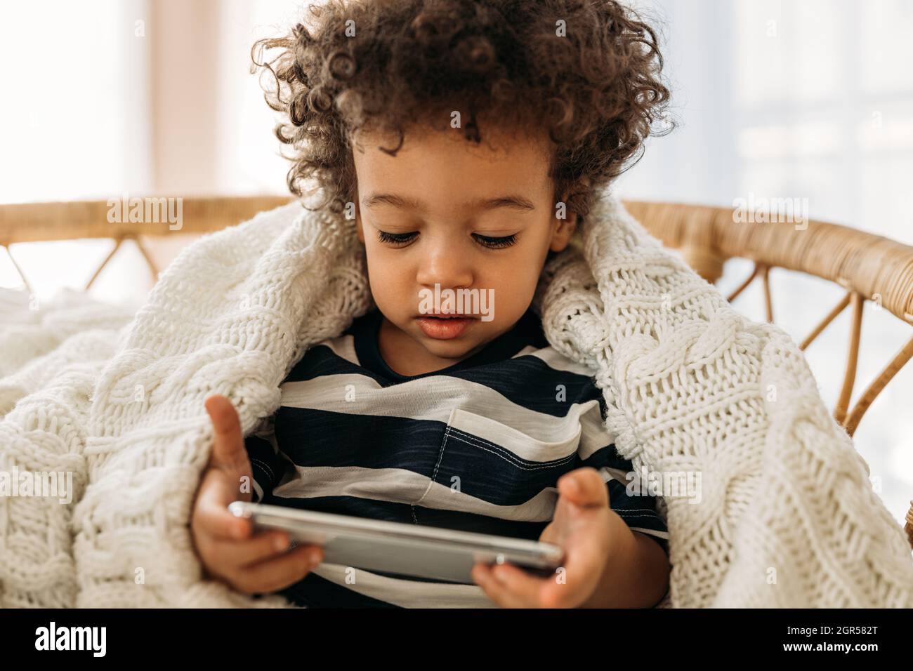 Cute Boy Holding Mobile Phone While Sitting On Floor Stock Photo - Alamy
