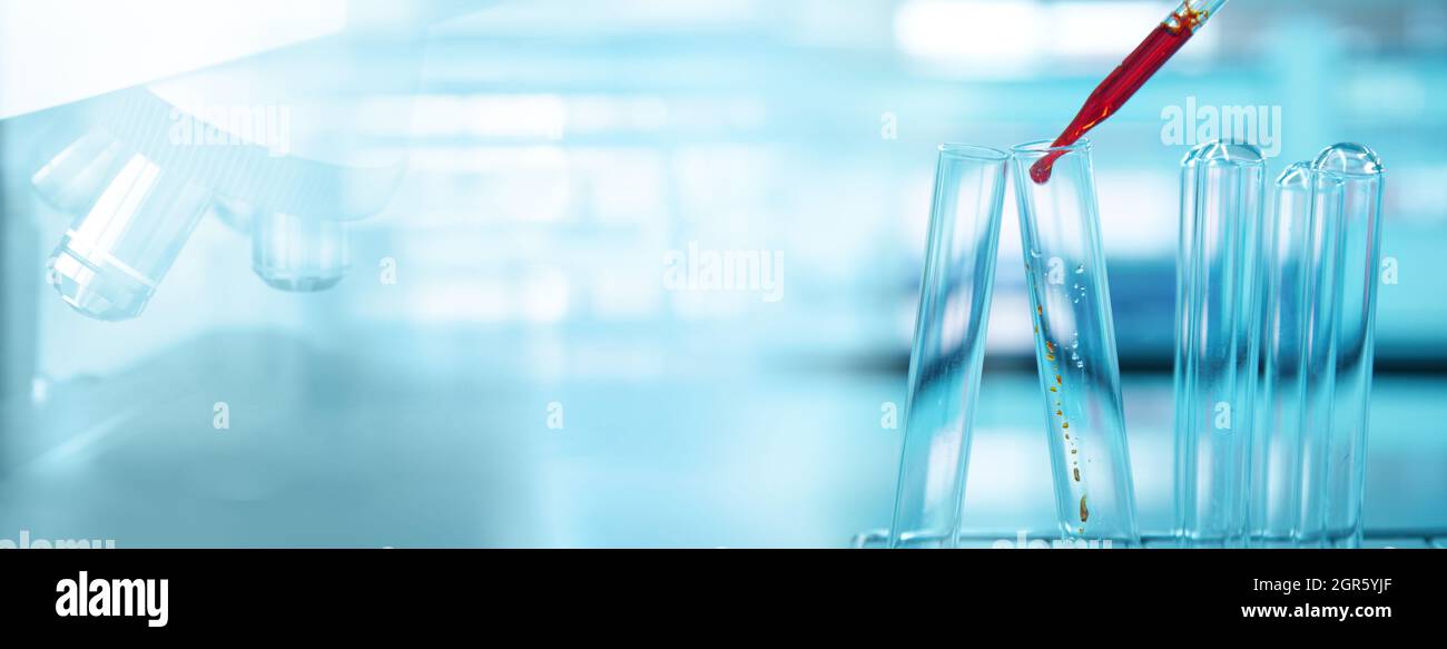 orange drop in glass test tube and microscope in soft blue light ...