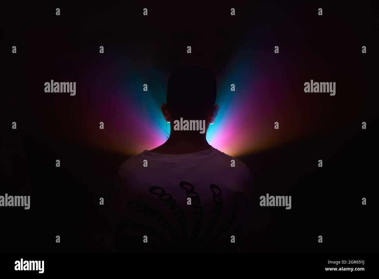 Close up shot on the back of a young guy looking to a colorful lights ...