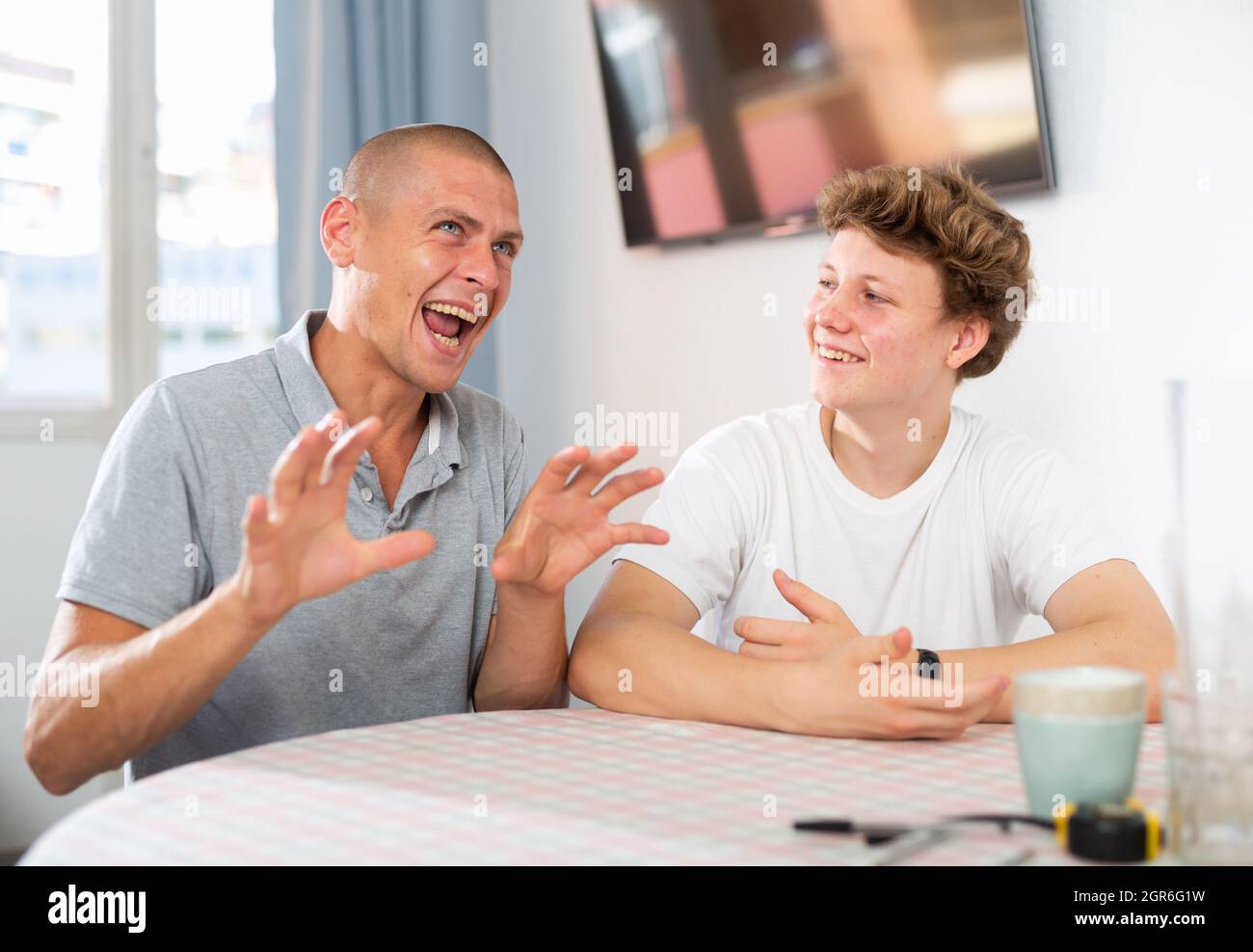Portrait of teen boy having conversation with man in home Stock Photo ...