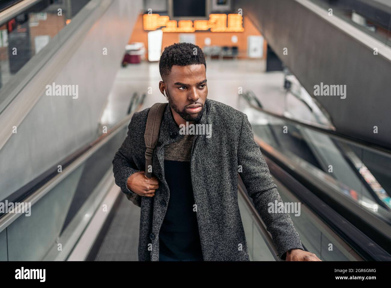 Man Looking Away While Standing On Escalator Stock Photo - Alamy