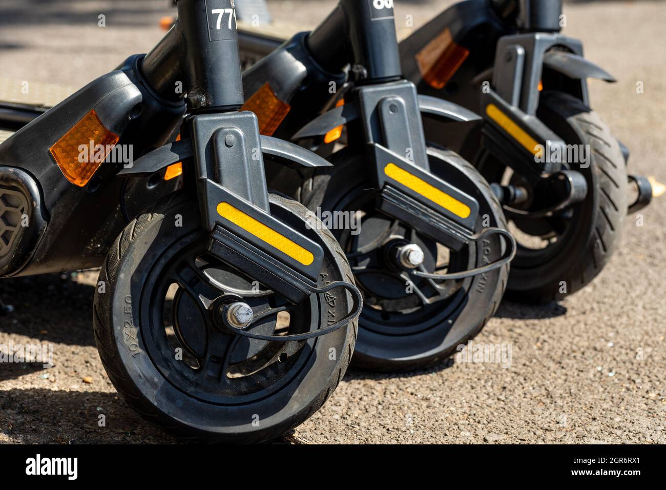 Close-up shot of motor scooters in a row parked outdoors on a concrete ...