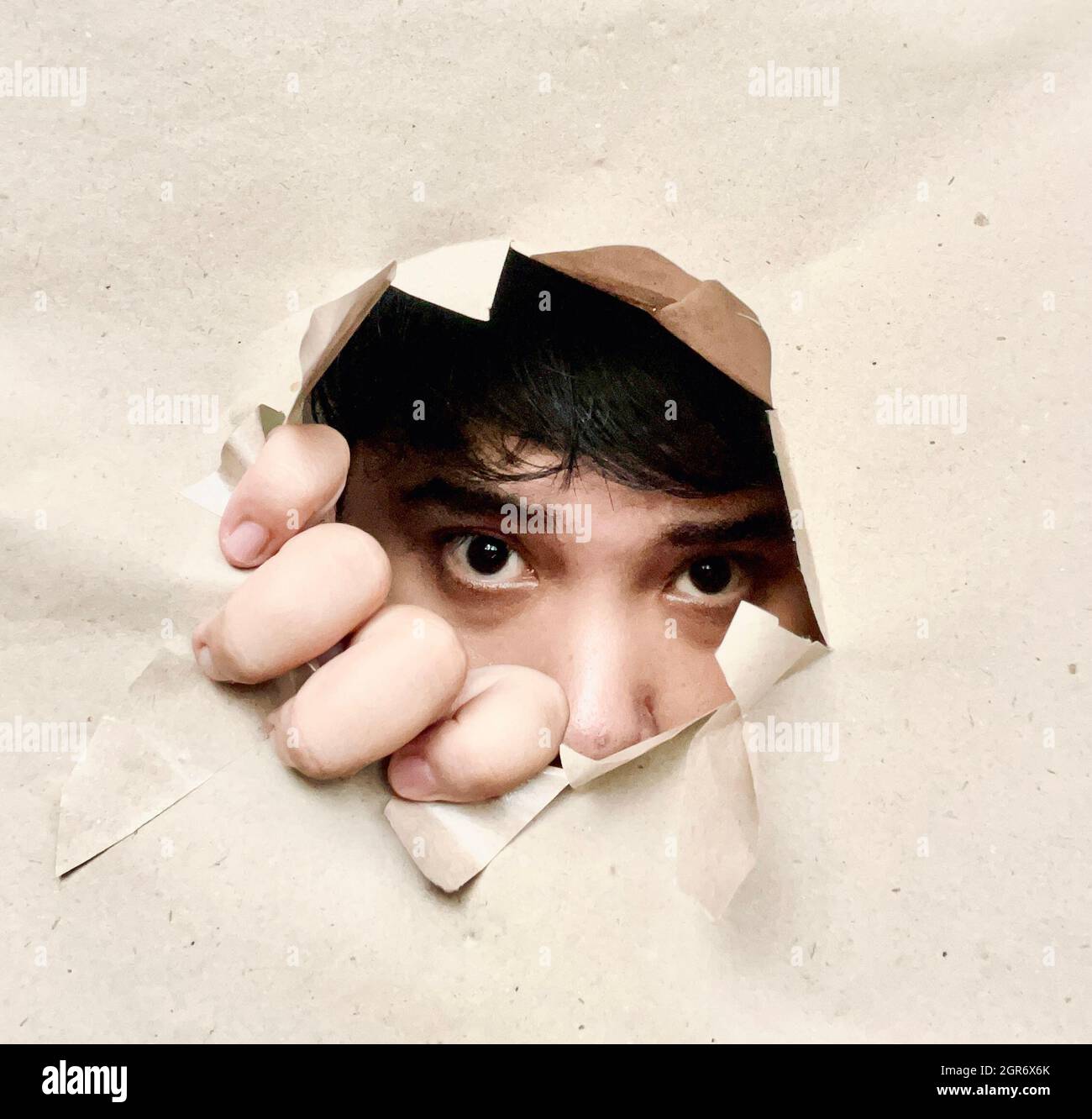 Man peeking through torn paper hi-res stock photography and images - Alamy