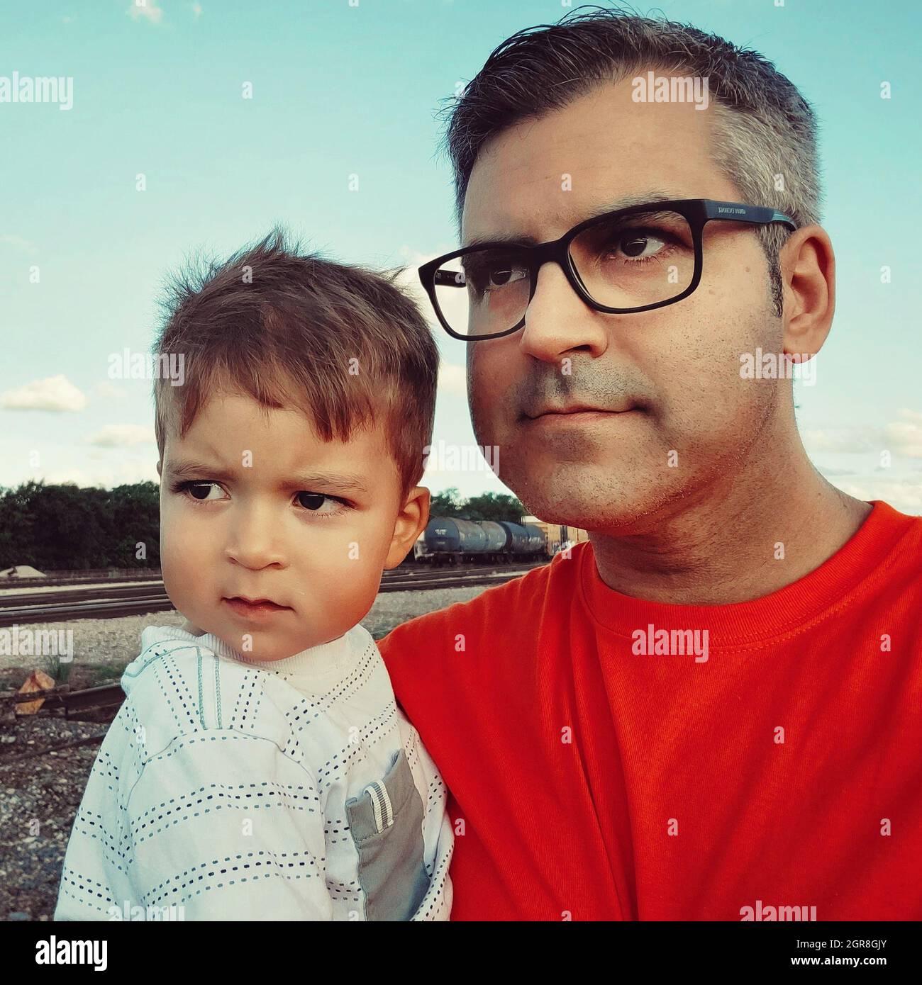 Portrait Of Man With Glasses Holding A Toddler Boy Looking Into The ...