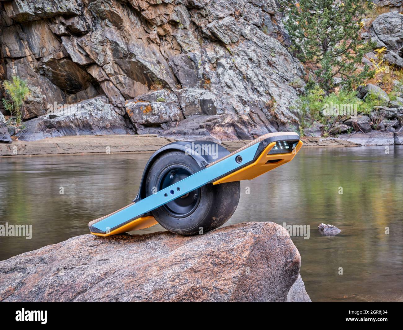 one-wheeled electric skateboard on a shore of mountain river with a ...