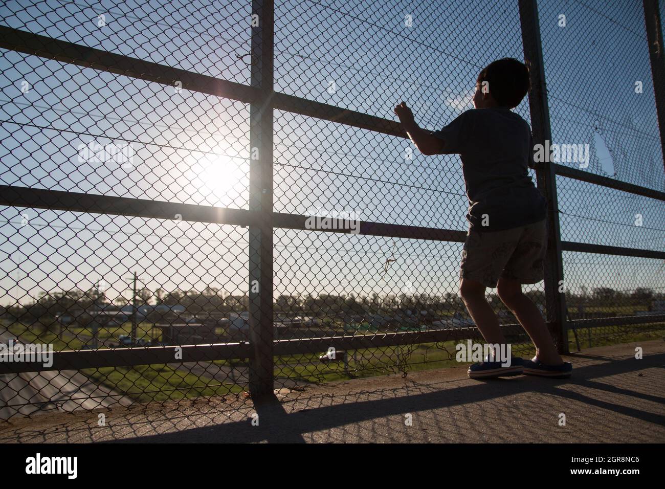 Boy looking through chainlink fence hi-res stock photography and images ...