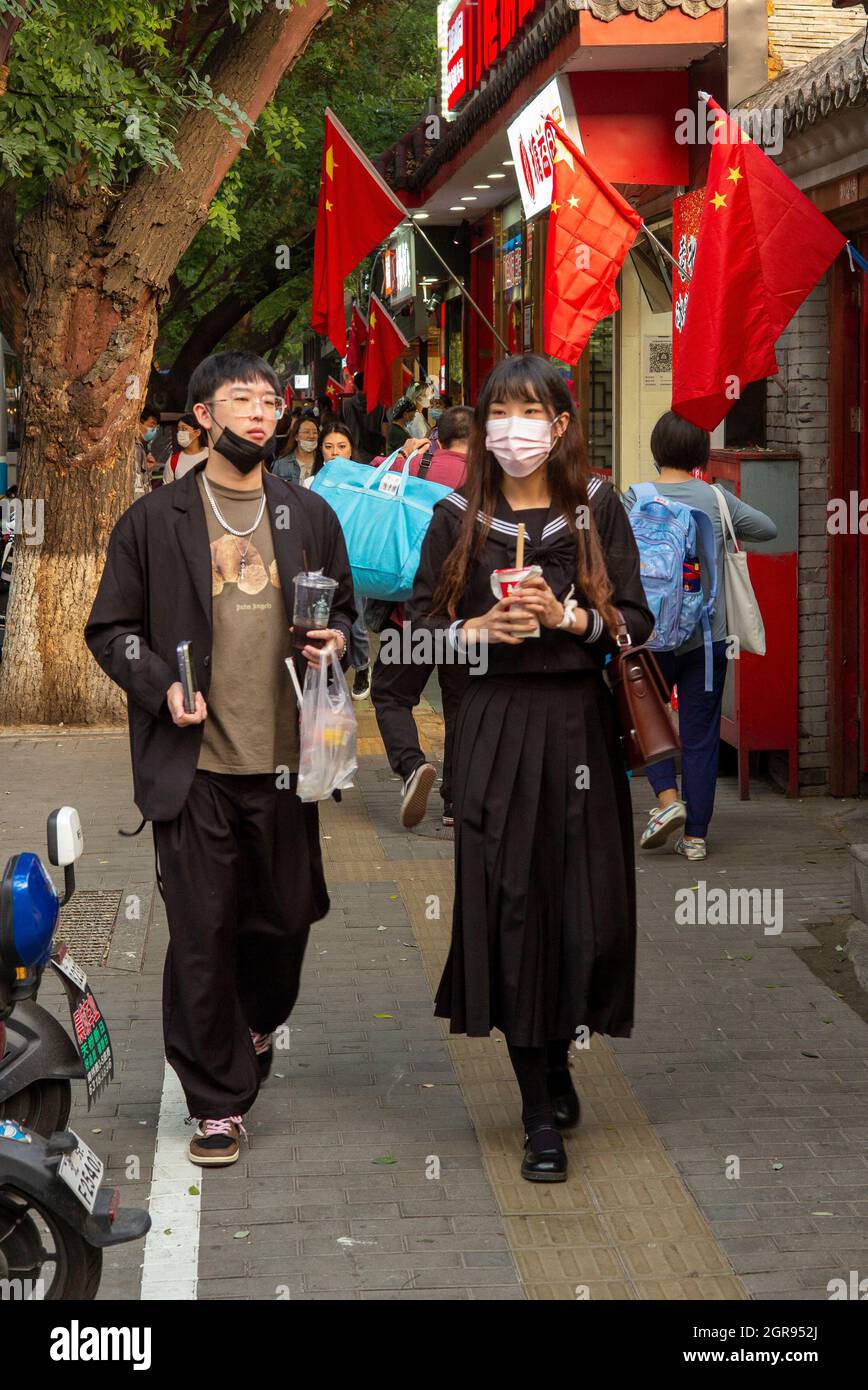 Beijing, China. 30th Sep, 2021. Passers-by walk down sidewalk next to ...