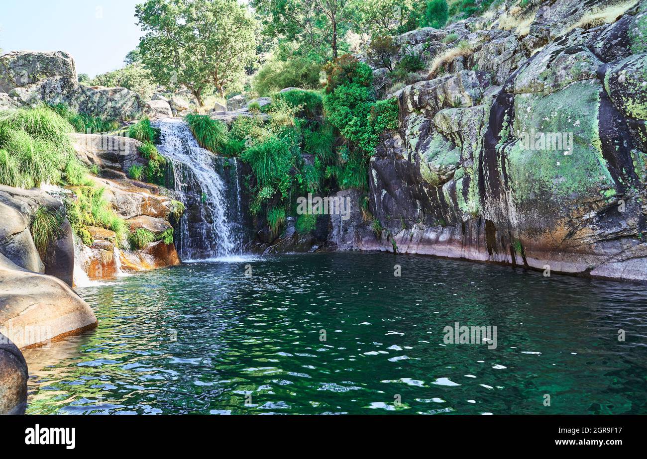 Scenic shot of a waterfall surrounded by forest mountains under the ...
