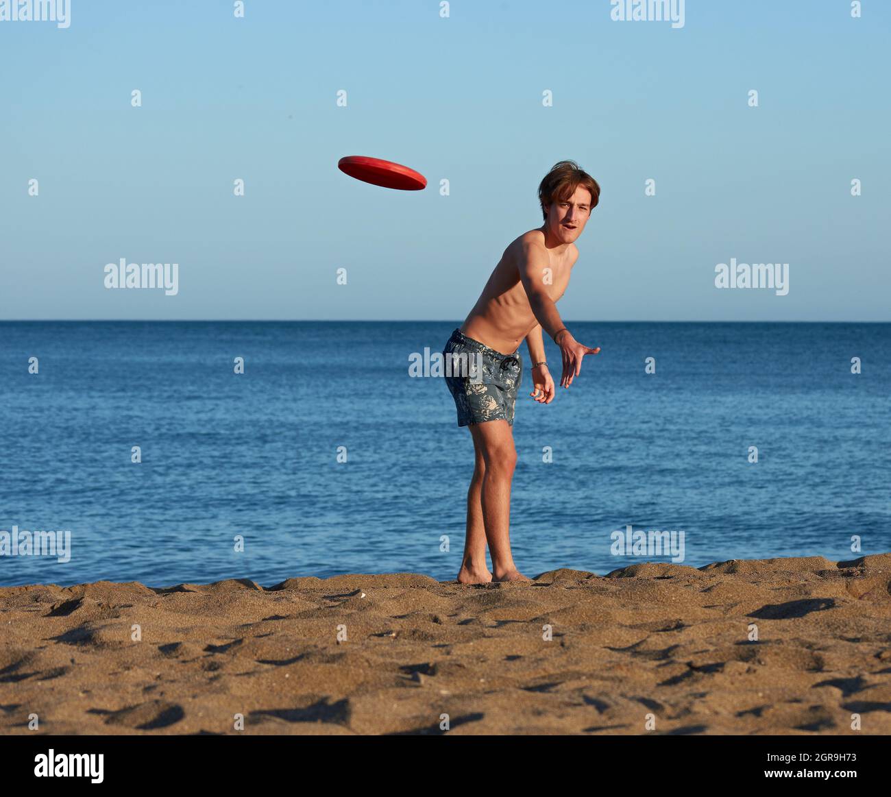 A Spanish attractive male playing frisbee on the sea background Stock ...
