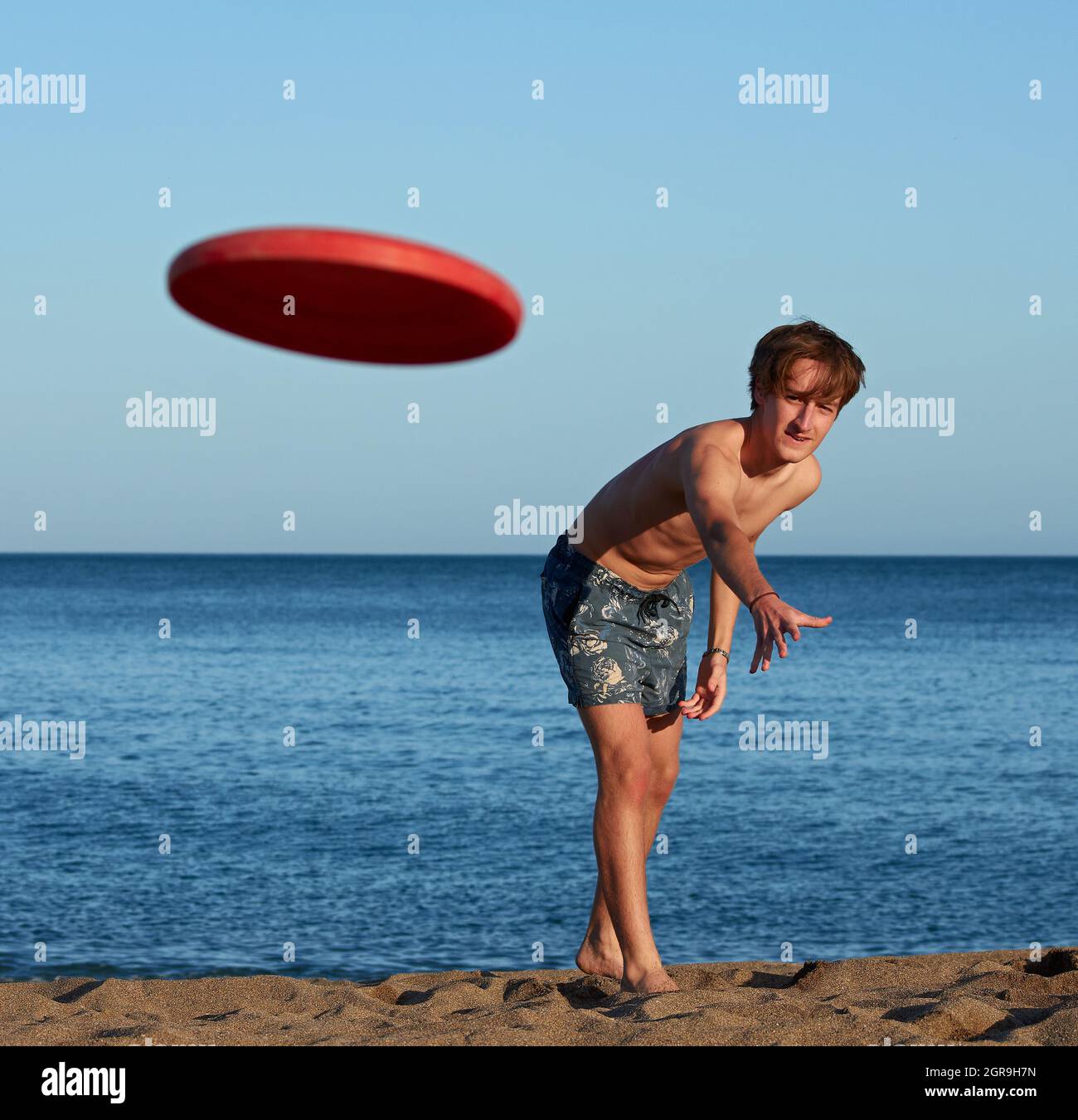 A Spanish attractive male playing frisbee on the sea background Stock ...