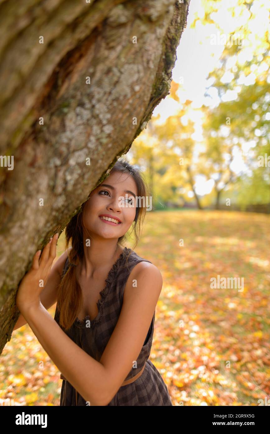 Pretty woman peeking behind tree hi-res stock photography and images ...