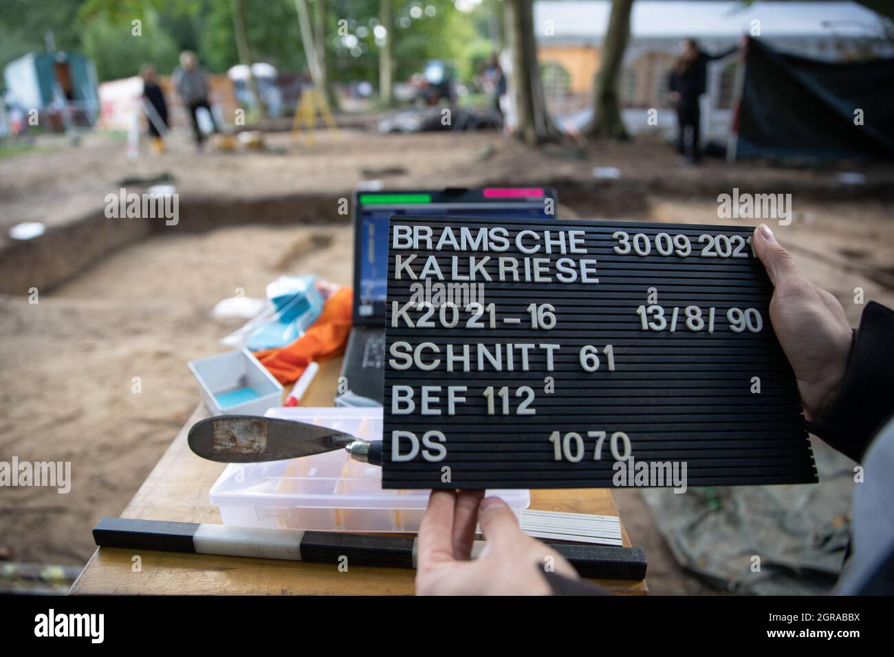 Bramsche, Germany. 30th Sep, 2021. An archaeologist holds a photo board ...