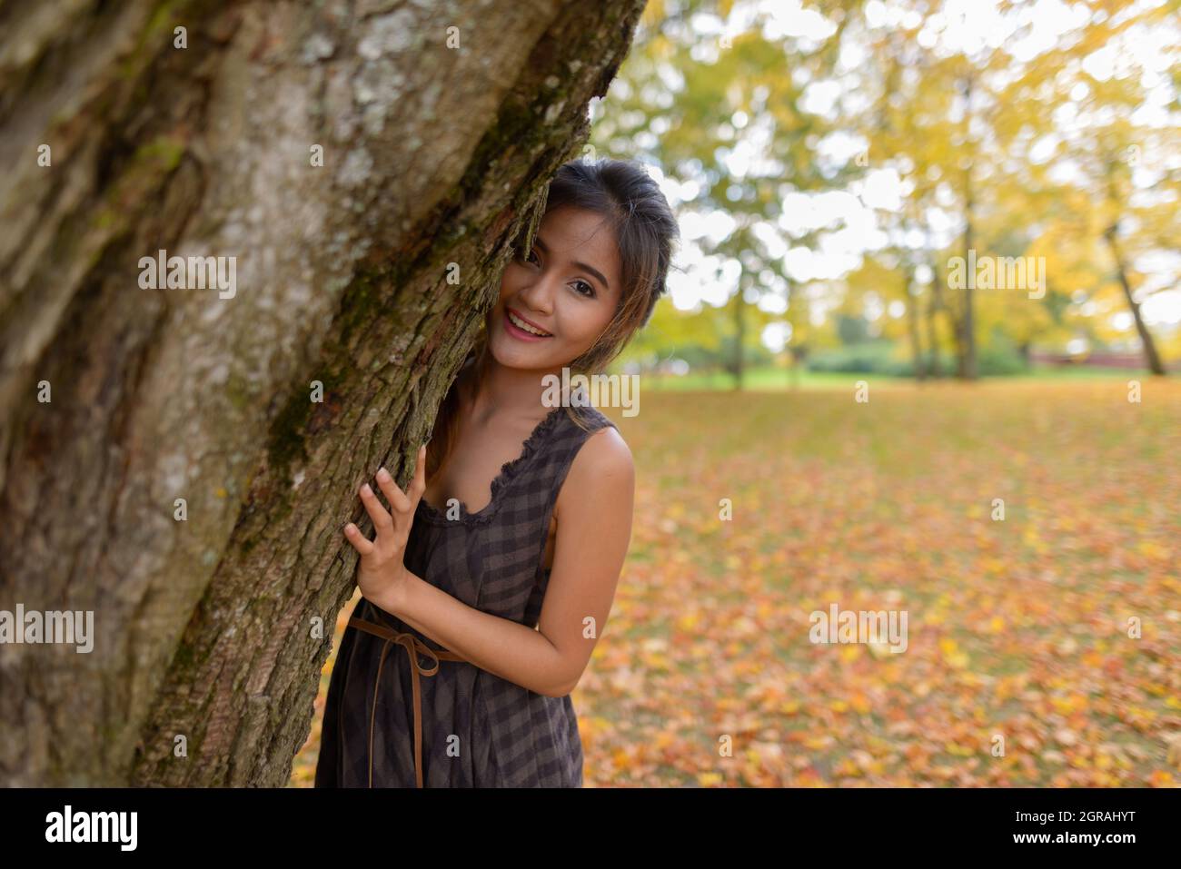 Pretty woman peeking behind tree hi-res stock photography and images ...