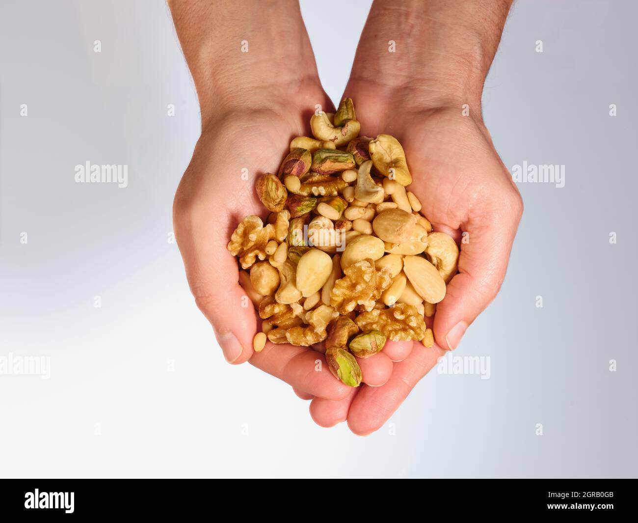 Nuts mix with seeds and dried fruits. Hands holding nuts on white ...