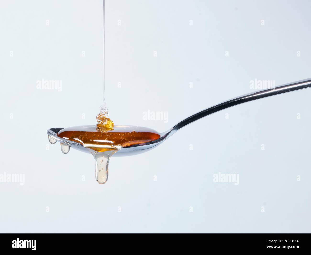 Honey dripping from metal spoon on white background Stock Photo - Alamy