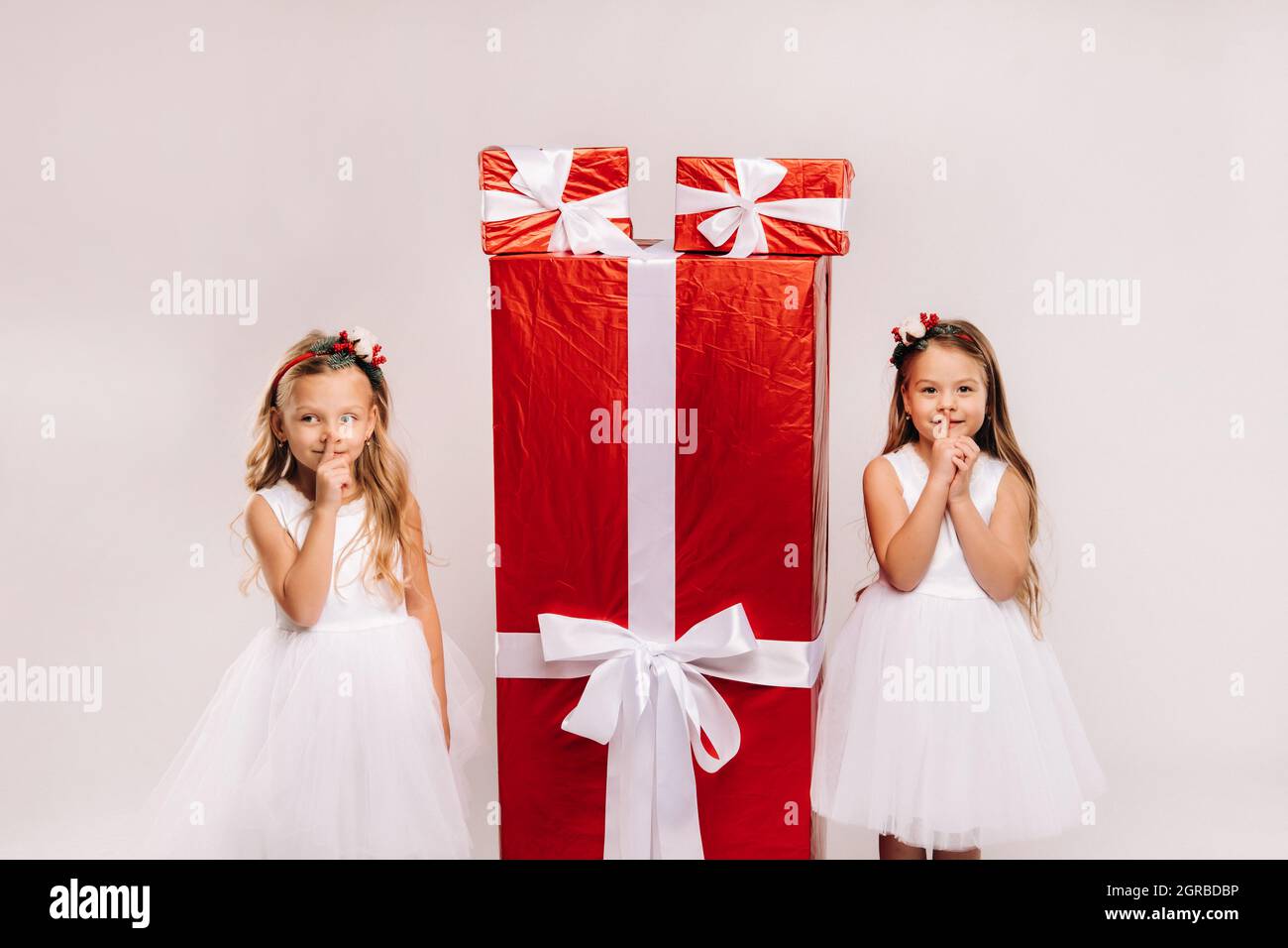 two little girls with Christmas gifts on a white background and a huge ...