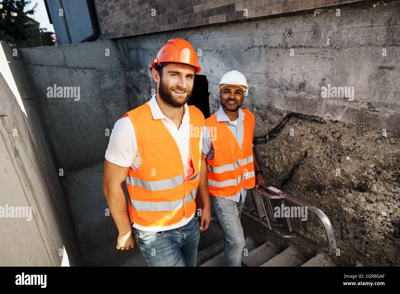Two young male engineers in uniform and hardhats working at ...