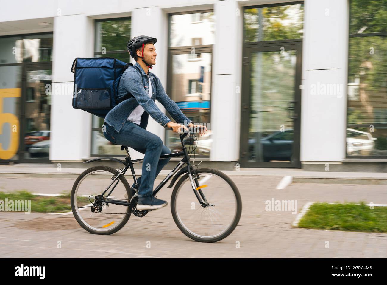 Side view of happy handsome young delivery man with thermo backpack ...