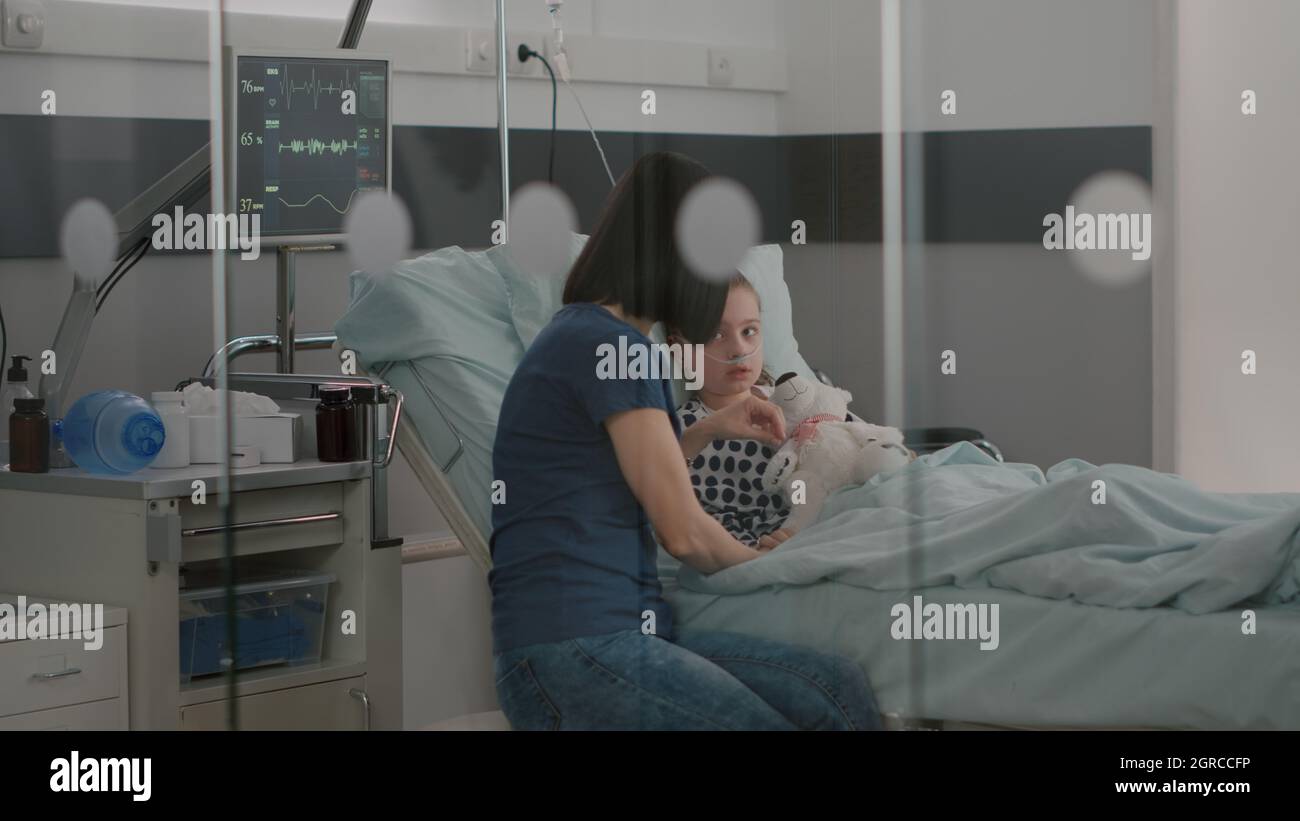 Hospitalized sick child resting in bed wearing nasal tube recovering ...