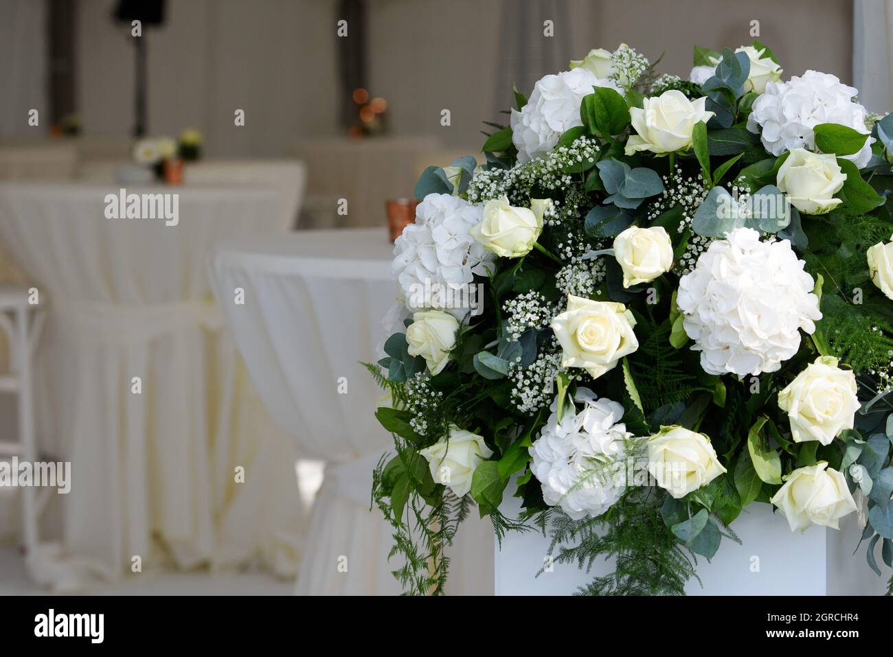 White roses in flower arrangement for a reception with defocussed ...