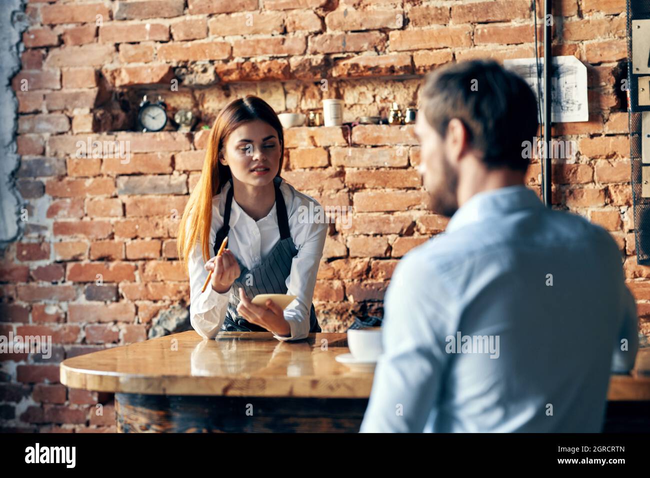 Young Couple Sitting At Restaurant Against Brick Wall Stock Photo - Alamy